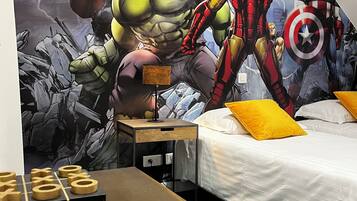 Quarto com cama, mesa de cabeceira e um mural na parede com super-heróis.
