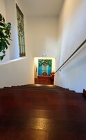 Uma escadaria de madeira leva a uma porta com um vitral retratando uma árvore.