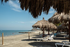 Na praia, areia branca, guarda-sóis, toalhas de praia 