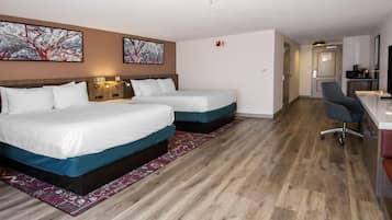 Quarto de hotel com duas camas, uma escrivaninha e uma cadeira.