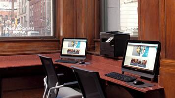 Sala de conferências com dois computadores de mesa, uma impressora e duas cadeiras.