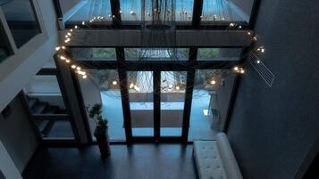 Um interior com vários níveis, com escada, área de estar e vista para o exterior.