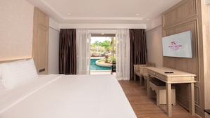 Quarto de hotel com cama, escrivaninha, televisão e vista para uma piscina ao ar livre.