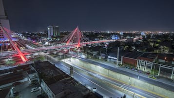Paisagem urbana noturna com uma ponte vermelha iluminada e uma autoestrada.
