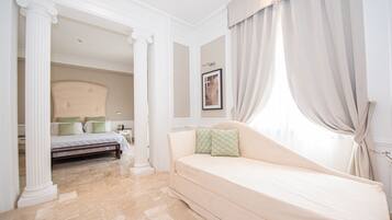 Um quarto com cama, sofá, um quadro na parede e janela com cortinas.