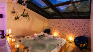 Um espaço de spa com hidromassagem, velas e vista por um claraboia.