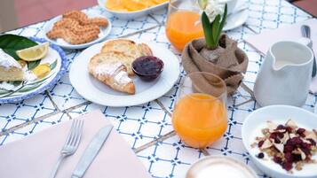 Uma mesa de café da manhã com pratos de comida, um jarro e um copo de suco de laranja.