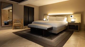 Quarto moderno com cama grande, abajures, um banquinho e um espelho.