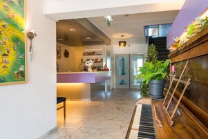 Um interior moderno com um piano, um mapa na parede e uma área de cozinha.