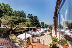 Um terraço com área de estar ao ar livre, piscina e vista para árvores e um edifício.