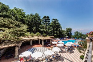 Uma área de piscina com guarda-sóis, cadeiras e vista para a floresta ao redor.