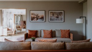 Uma sala de estar moderna com um sofá, duas fotos emolduradas de veados na parede e um abajur.