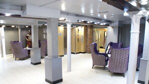 Um lobby com área de recepção, elevadores e assentos com design moderno.