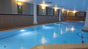Piscina interna com paredes e piso revestidos em azulejo e teto com iluminação embutida.