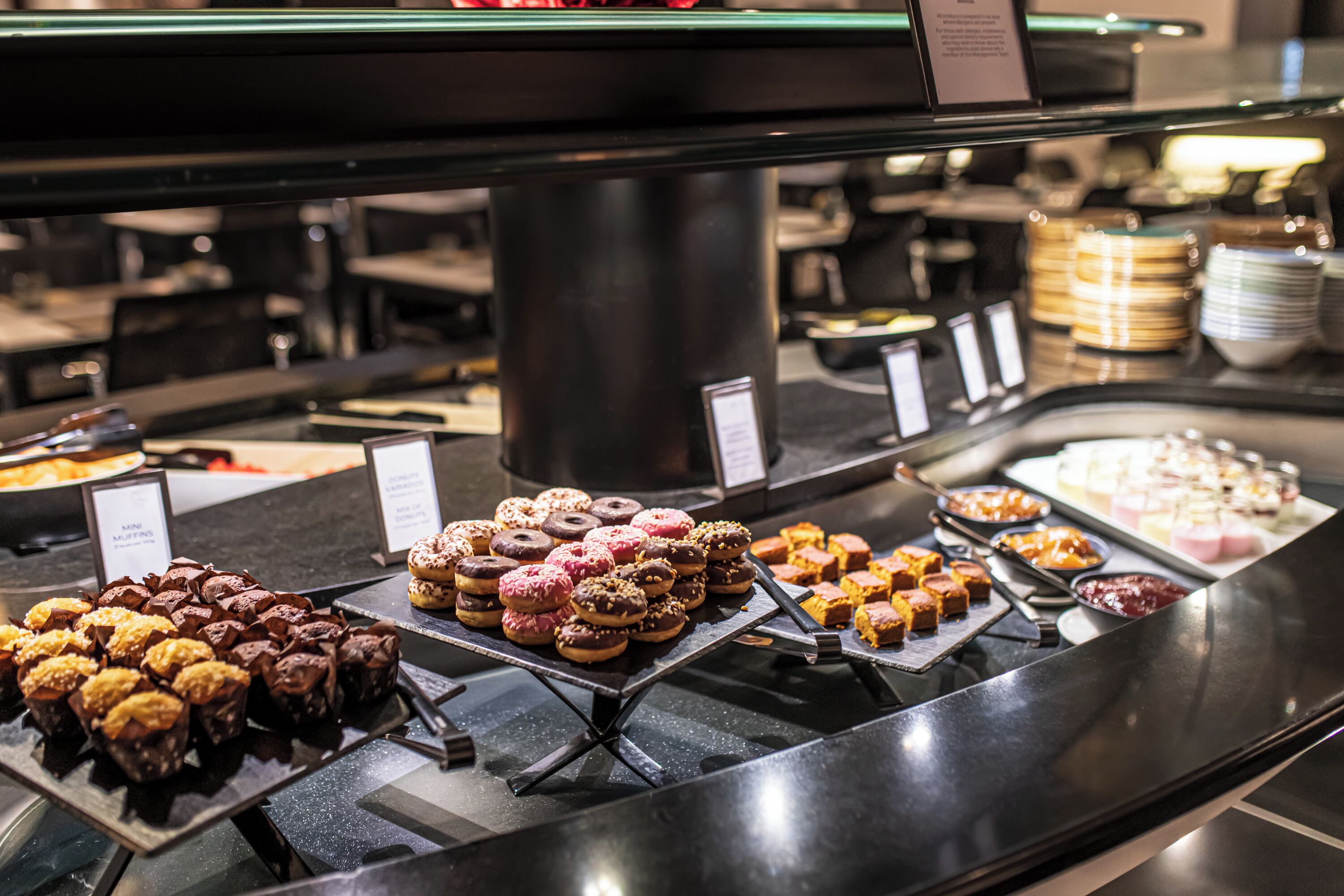 Buffet com diversos alimentos, incluindo donuts e doces.