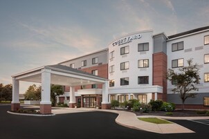 Hotel Courtyard by Marriott com entrada coberta, fachada de tijolos e várias janelas.