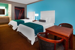 Quarto de hotel com duas camas, uma escrivaninha e uma cadeira.