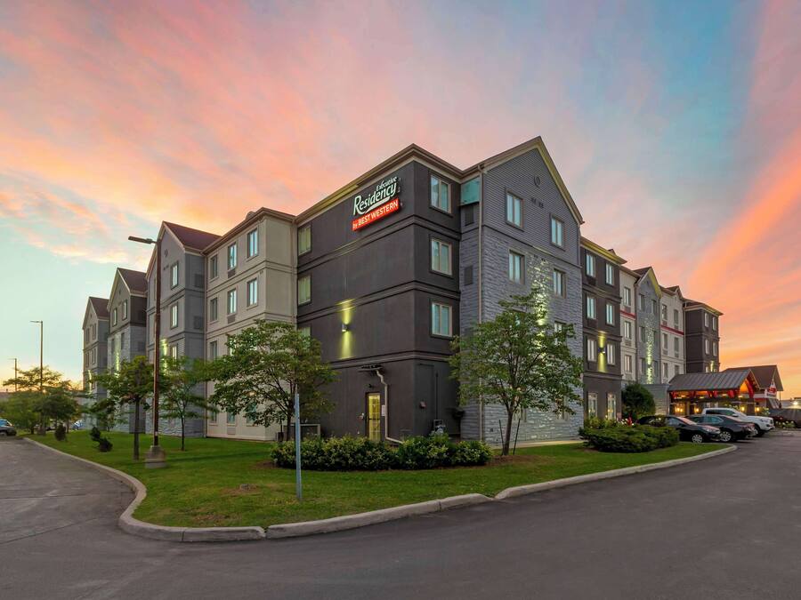 Um hotel com vários andares e design moderno, com destaque para a placa com as marcas 'Residence' e 'Best Western'.