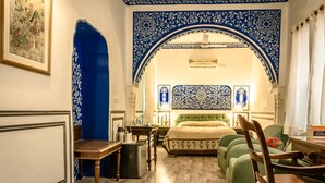 Um quarto com cama, escrivaninha, cadeira e mesa.