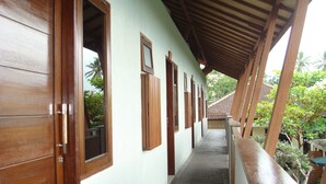 Corredor com portas e janelas de madeira, uma galeria coberta e vista para o verde lá fora.