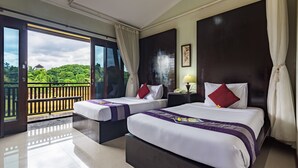 Quarto de hotel com duas camas, varanda e vista para área verde.