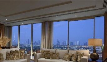 Quarto de hotel em um edifício alto com uma janela grande que oferece vista para a cidade.