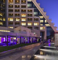 Um hotel moderno com piscina, área de estar externa e fachada bem iluminada.