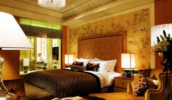 Quarto de hotel com uma cama grande, duas mesas de cabeceira, uma cadeira e um espelho.