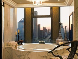 Um banheiro luxuoso com uma banheira grande, vista para o horizonte da cidade e um candelabro.