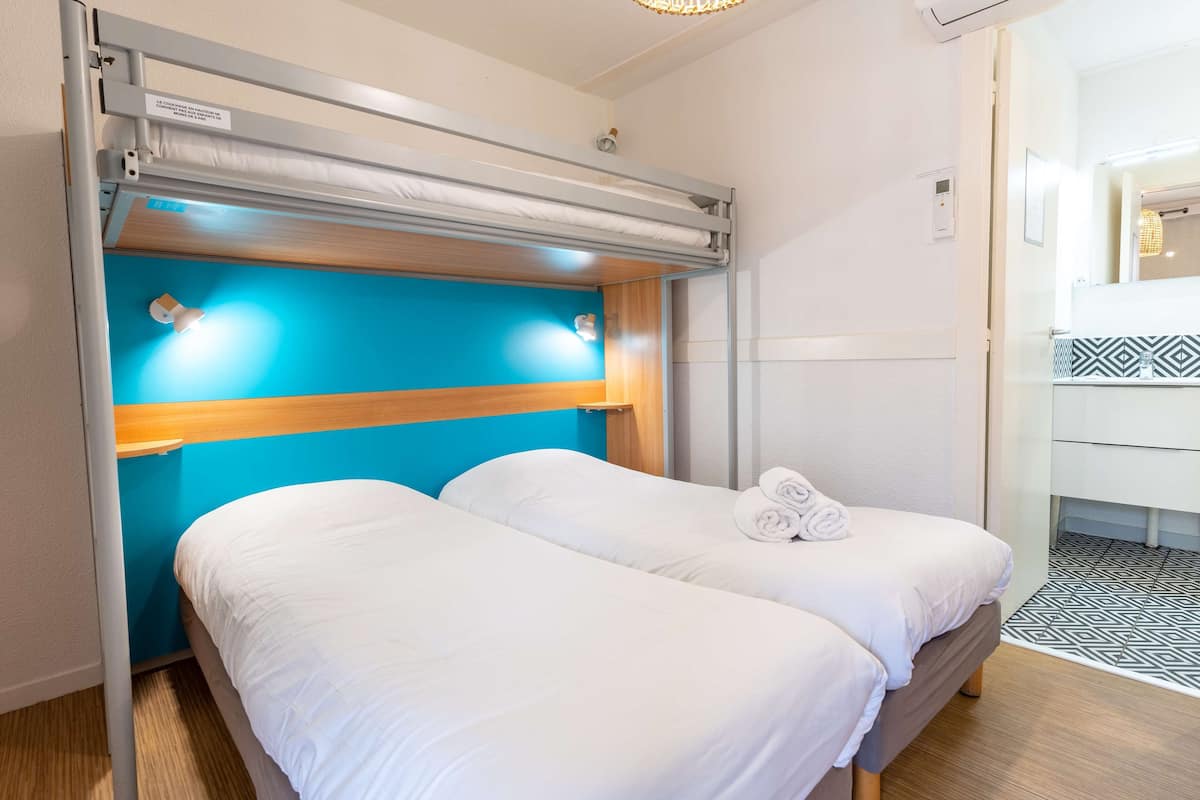 Quarto de hotel com duas camas de solteiro, cabeceira de madeira e parede azul decorativa.