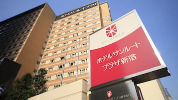 Um letreiro de hotel com texto em japonês e um logotipo, indicando o nome do hotel 'Hotel Sunroute'.