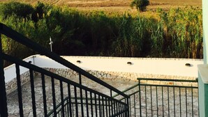Escadaria que leva a um terraço com vista para uma paisagem rural, incluindo campos e colinas.