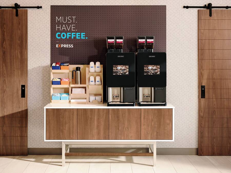 Uma estação de café com duas máquinas de café, diversos tipos de cápsulas e xícaras.