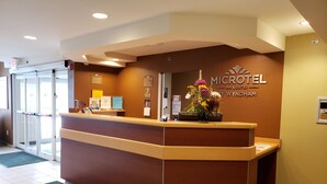 Uma receção do Microtel Inn & Suites, com balcão castanho, um arranjo de flores e uma placa acima do balcão.