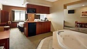 Quarto de hotel com cozinha, mesa de jantar e uma banheira grande.