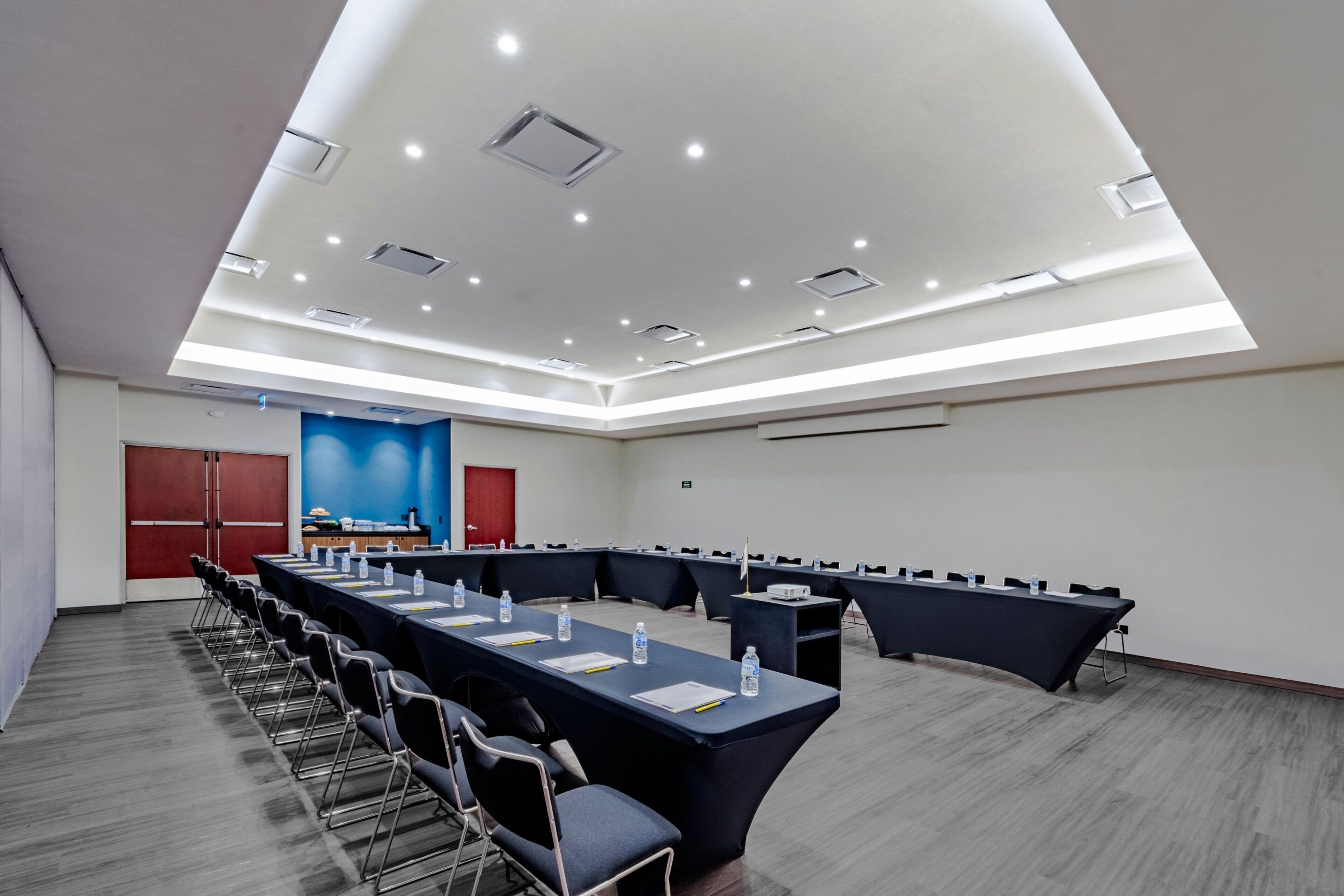 Uma sala de conferências com uma mesa comprida, cadeiras e uma parede azul.