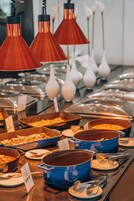 Disposição de buffet com diversos pratos, luzes de serviço azul e vermelha e utensílios de servir transparentes.