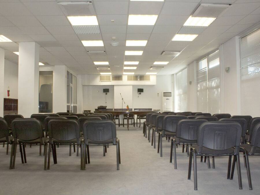 Uma sala de conferências com fileiras de cadeiras, uma mesa comprida e um quadro branco.