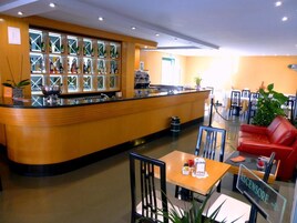 Um saguão de hotel com balcão de recepção, área de estar e bar.