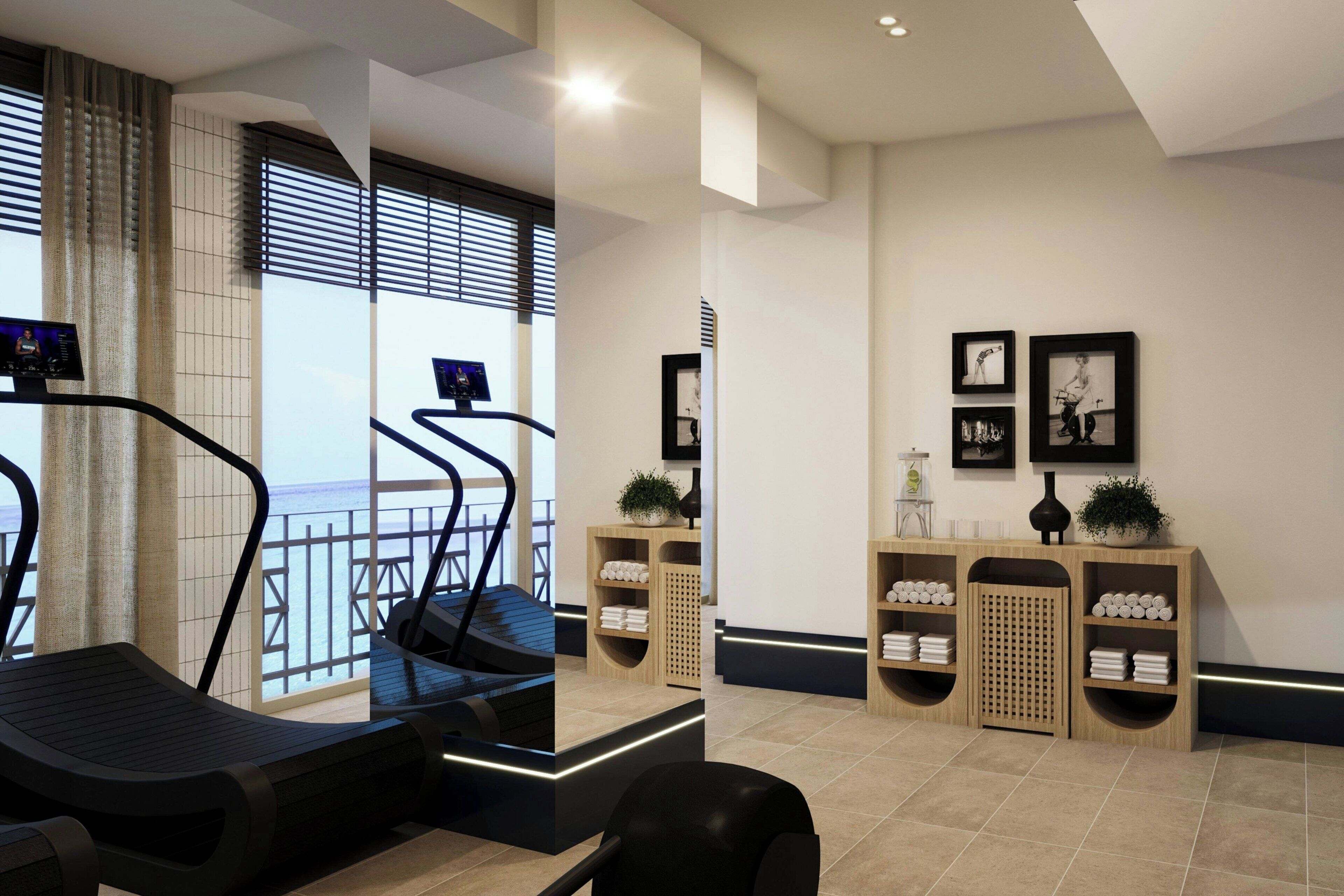 Ginásio com equipamento de exercícios, uma receção e vista para o mar.