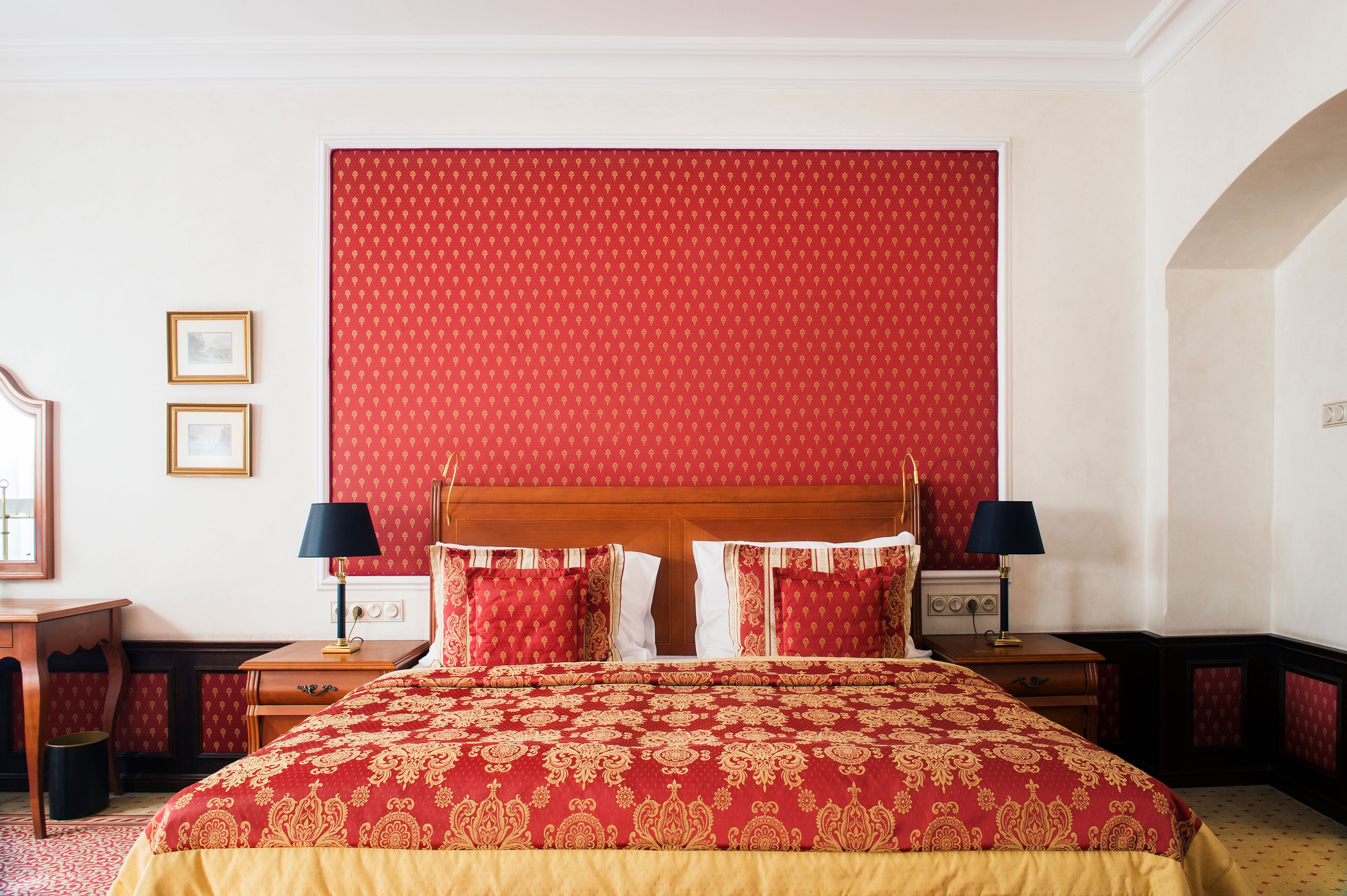 Quarto de hotel com uma cama grande, duas mesas de cabeceira, uma escrivaninha e um espelho.