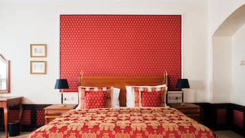Quarto de hotel com uma cama grande, duas mesas de cabeceira, uma escrivaninha e um espelho.