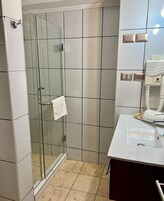Um banheiro moderno com box de vidro, pia branca e porta-toalhas.