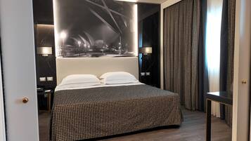 Quarto de hotel moderno com uma cama grande, um mural da paisagem urbana na parede e vista do céu noturno.