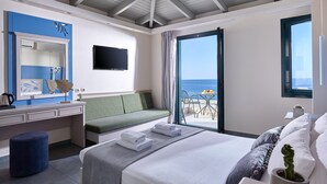 Quarto de hotel com cama, escrivaninha, cadeira, mesa pequena, planta em vaso e vista para o mar.