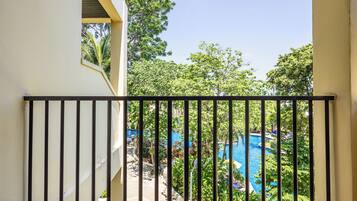 Varanda com guarda-corpo de metal preto, vista para uma piscina rodeada por vegetação exuberante.