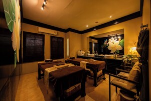 Uma sala de spa com mesas de massagem, uma pia e um espelho.