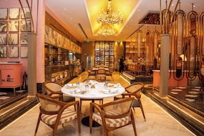 Uma sala de jantar com mesas redondas, cadeiras de madeira e um candelabro.