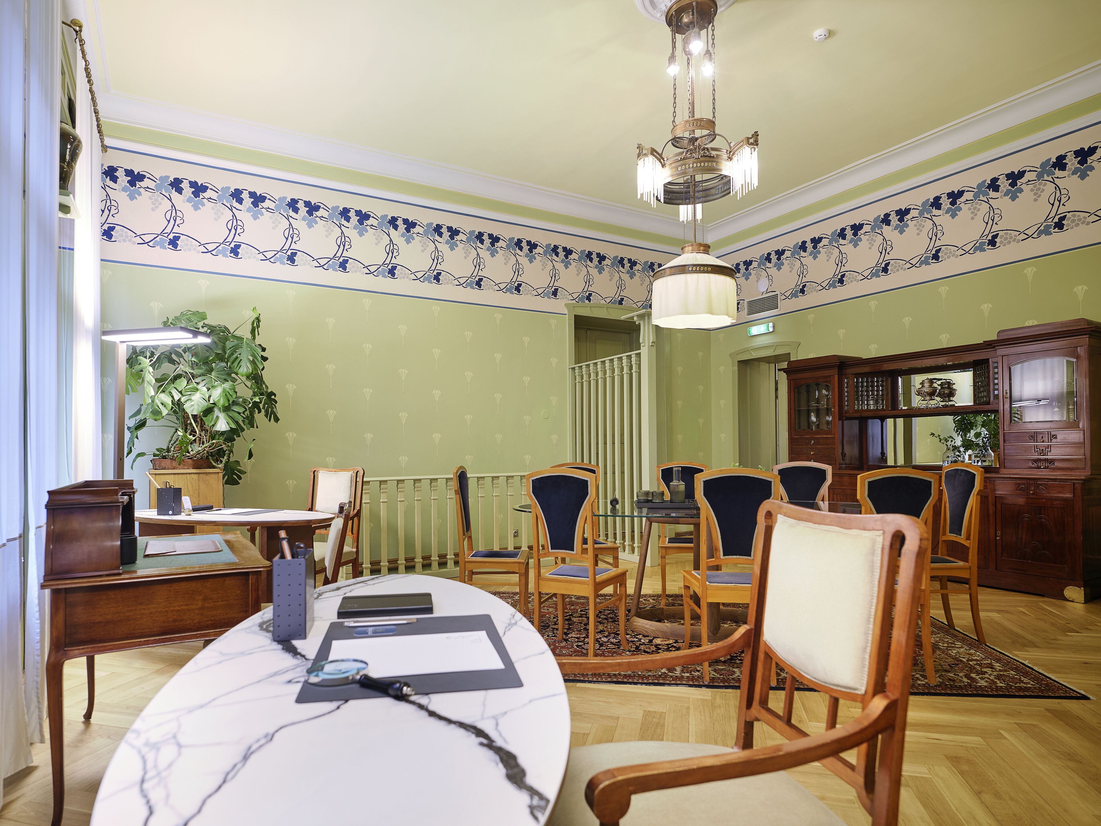 Uma sala de jantar formal com uma mesa de mármore, cadeiras de madeira e um lustre.