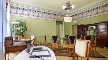 Uma sala de jantar formal com uma mesa de mármore, cadeiras de madeira e um lustre.